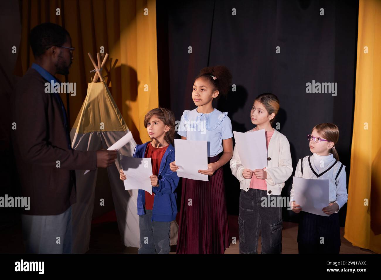 Diverse group of young children actors listening to drama teacher ...