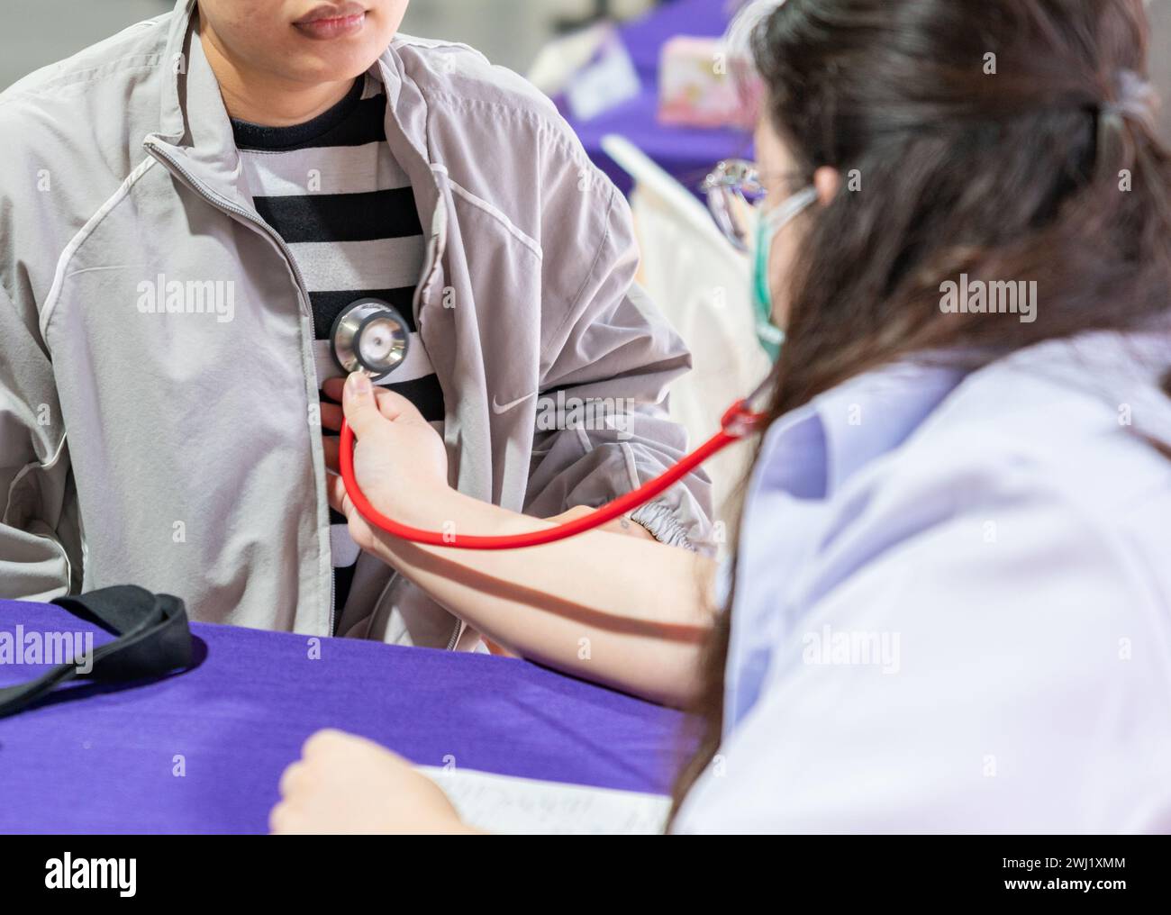 Doctor checking heart and pulse condition on staff in hospital with ...