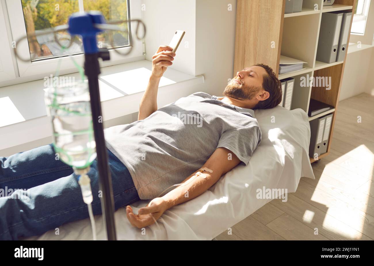 Male patient using mobile phone while getting intravenous vitamin ...