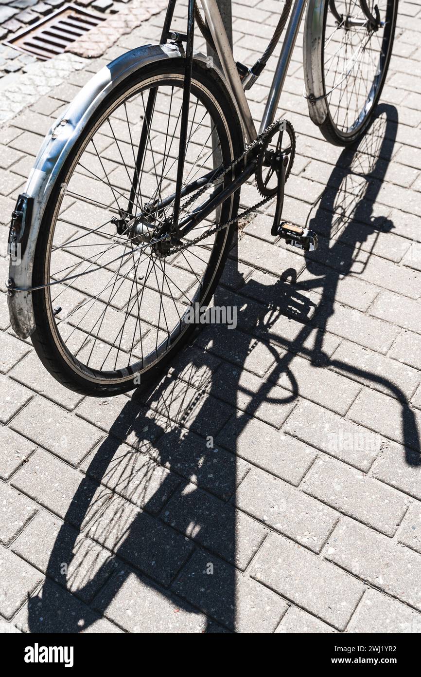 Iron road bicycle on a city street, casting a shadow in the sunlight ...