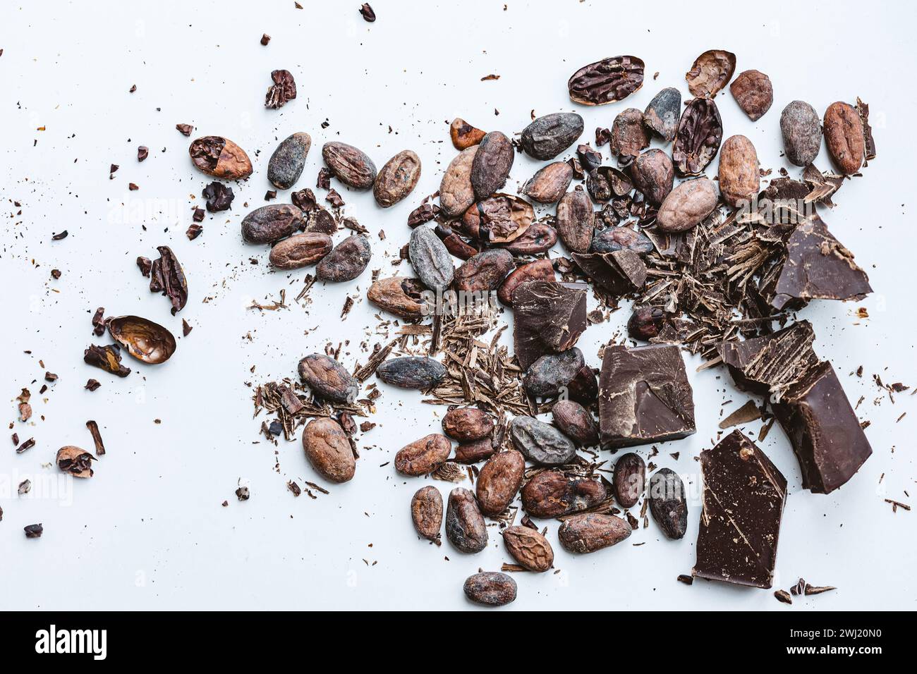 Cocoa beans and broken chocolate on white background. Top view copy ...