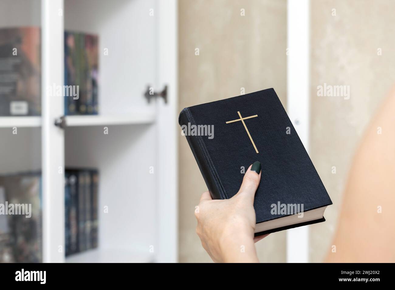 man takes out a bible from a bookcase. man putting away bible in ...