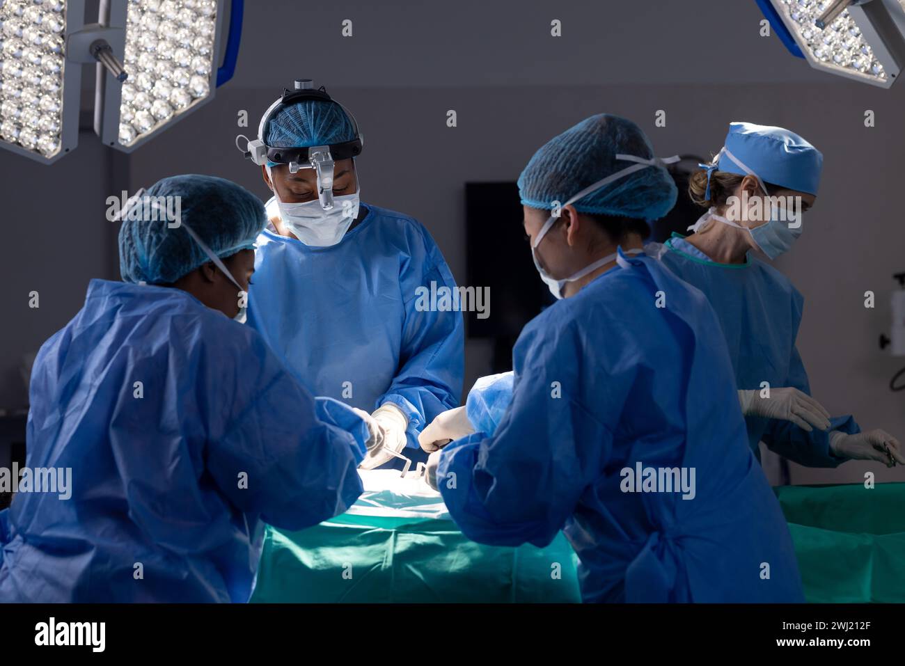 Diverse female doctors with face masks doing surgery in hospital ...