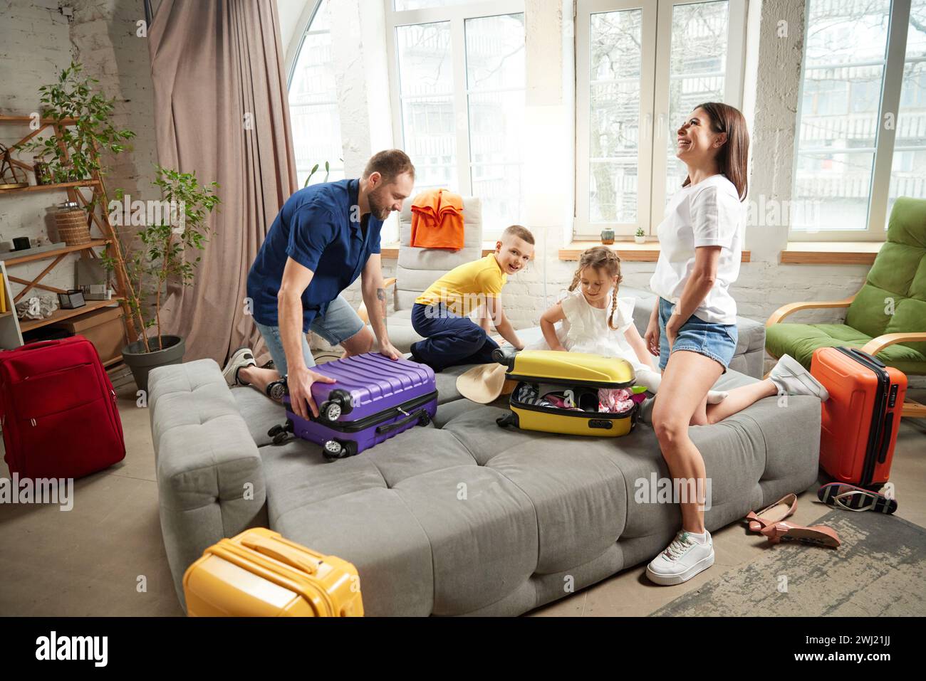 Parents and kids engaged in packing for trip. Husband and wife ...