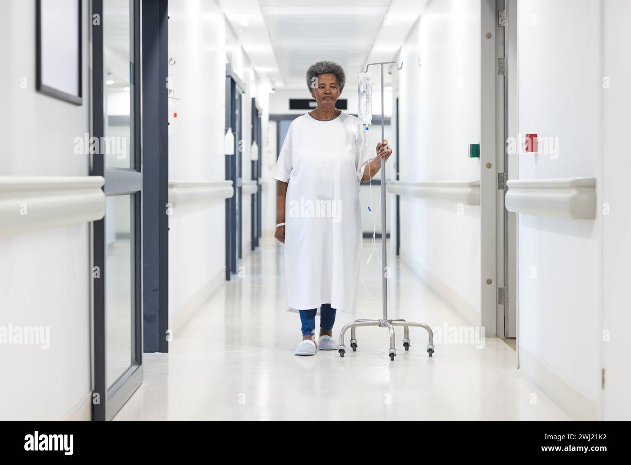 African american senior female patient with drip walking in hospital ...