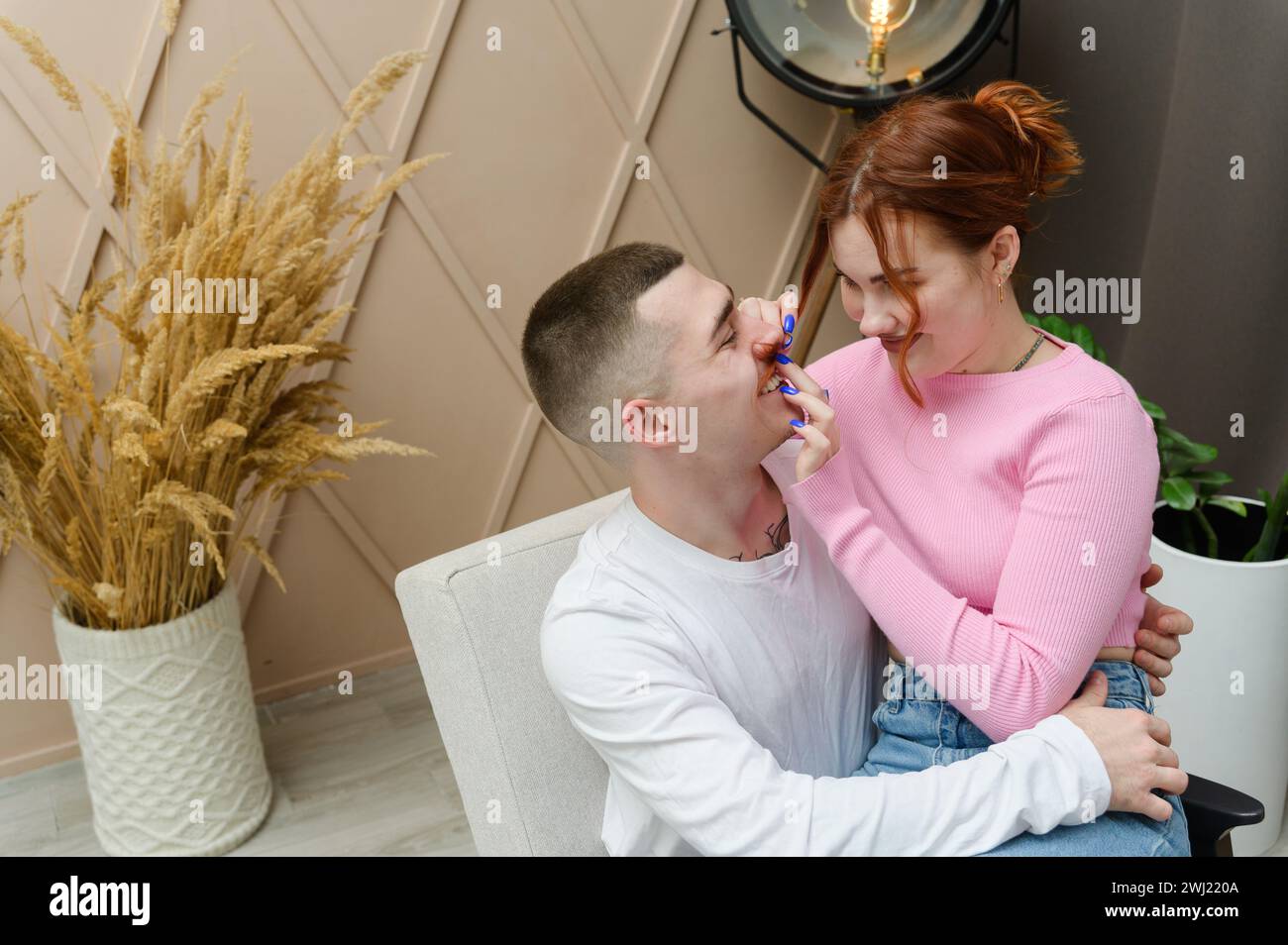 A couple hugs while sitting in a chair. A girl sits on a man's lap ...