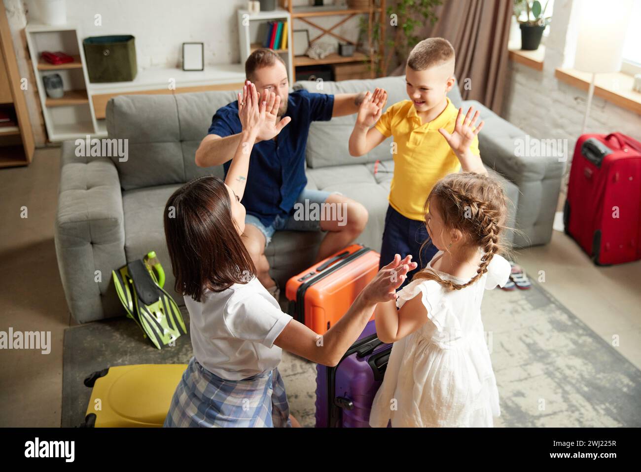 Parents and children packing backpacks at home, giving high five ...