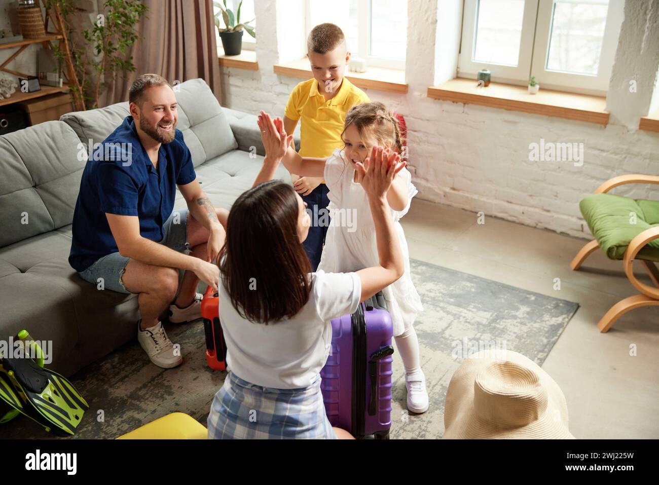 Parents and children packing backpacks at home, giving high five ...