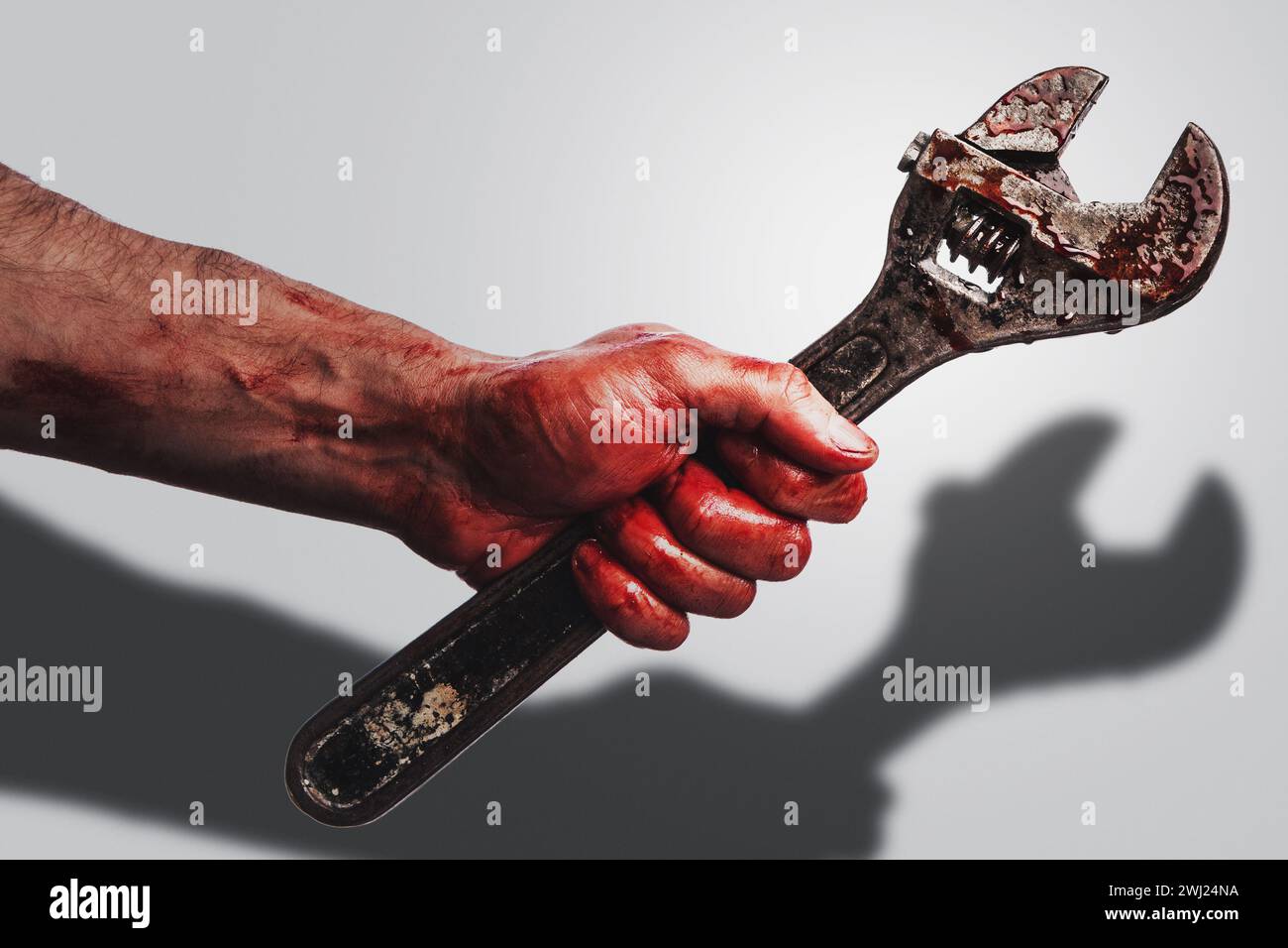 Male hand with adjustable spanner in blood stains casting shadow on ...