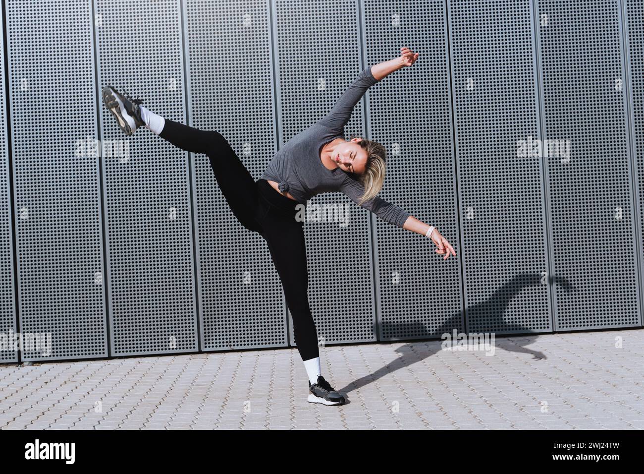 Expressive woman dancer performing against background with modern steel ...