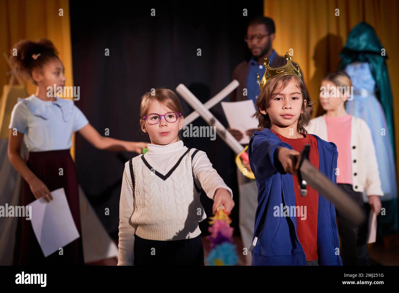 Waist up portrait of boy and girl standing on stage in theater and ...