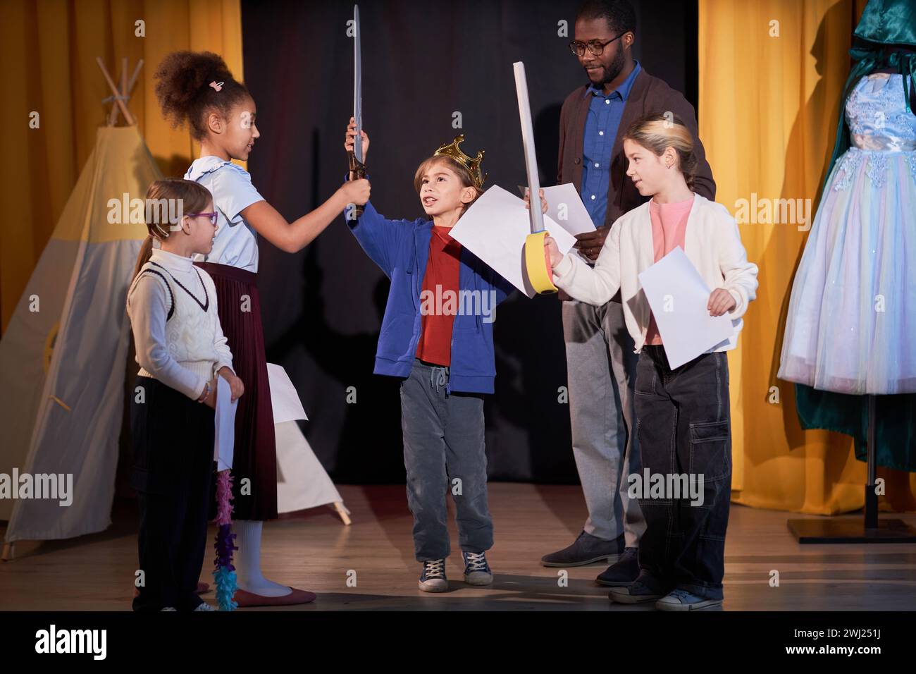 Full length portrait of children rehearsing school play on stage in ...