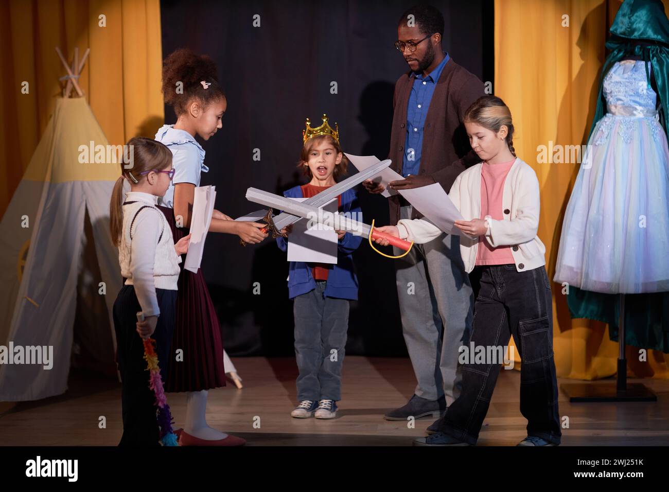 Full length portrait of children rehearsing school play on stage in ...