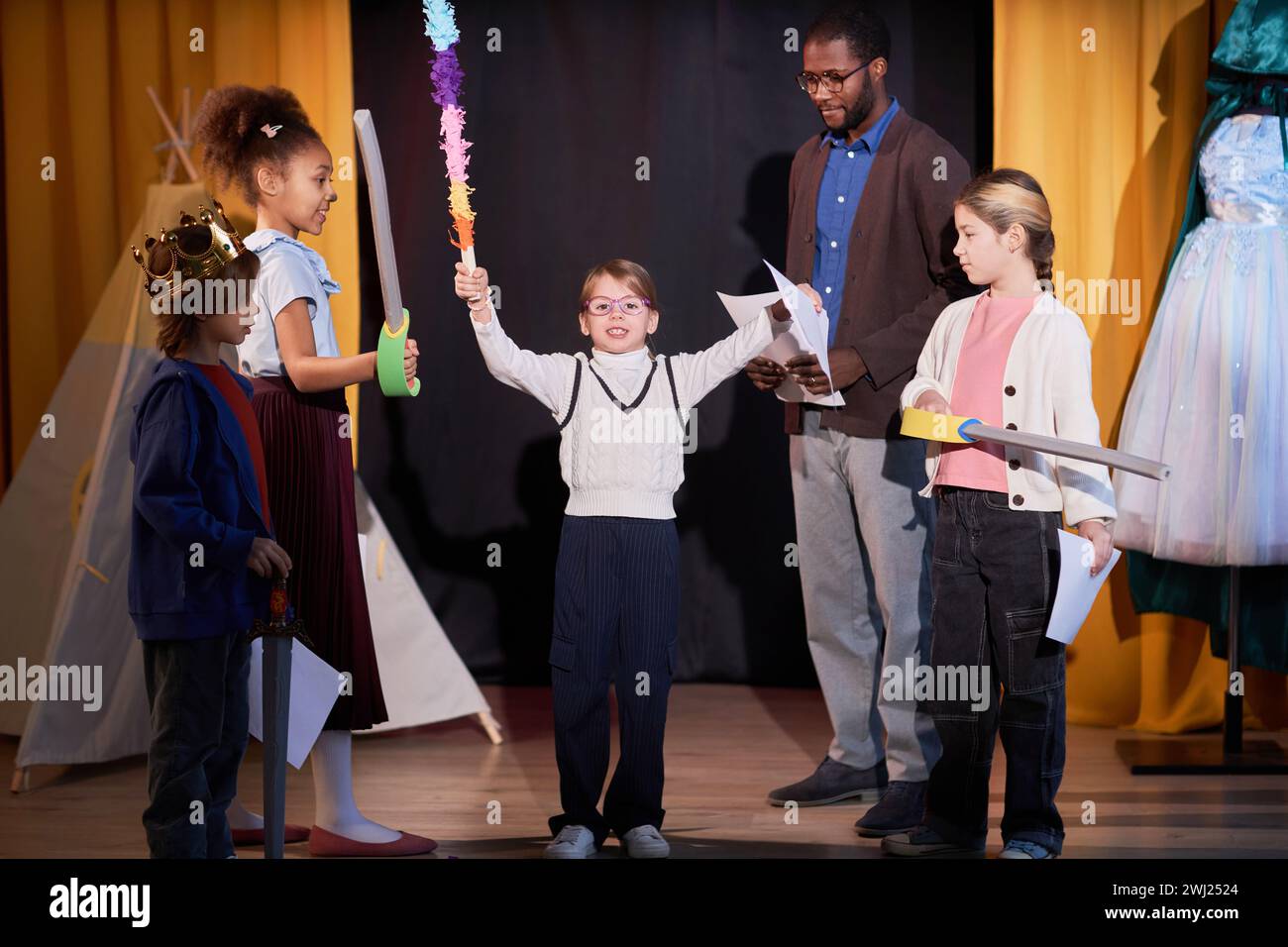 Full length portrait of young girl standing on stage rehearsing school ...