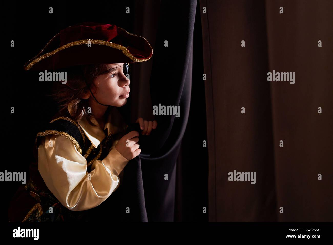 Side view portrait of little boy wearing costume peeking over curtain ...