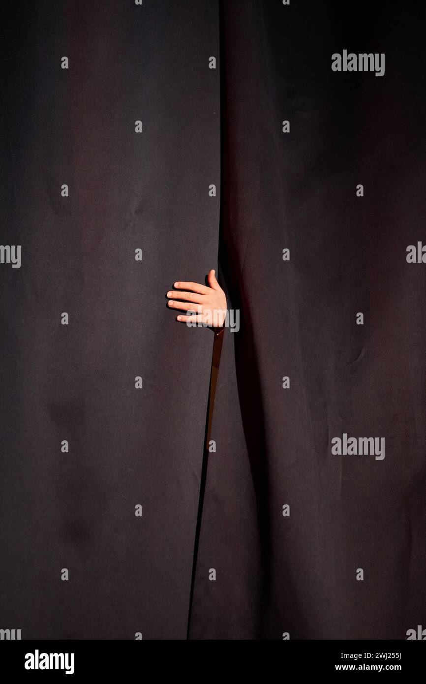 Close up of tiny childs hand peeking from behind curtain backstage in ...