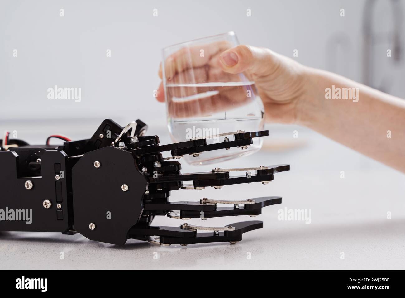 Robotic caregiver extending a hand with a glass of water to young woman ...