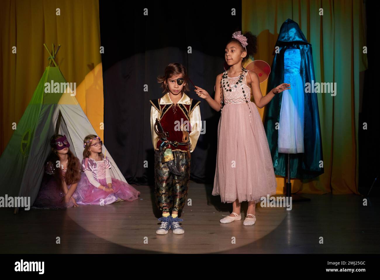Full length portrait of young boy and girl wearing costumes acting on ...