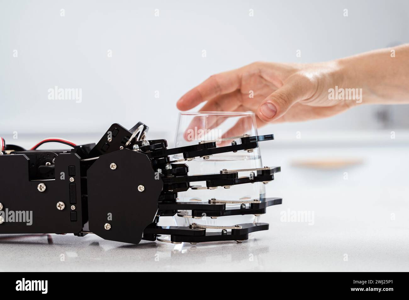 Robotic caregiver extending a hand with a glass of water to young woman ...