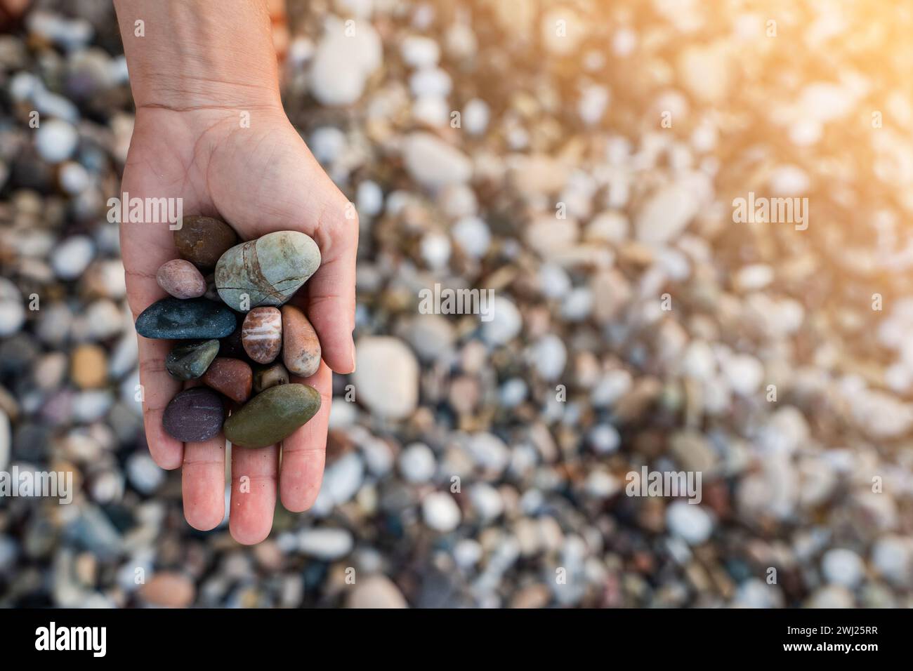 Female hand with heap of pebbles on shingle beach Stock Photo - Alamy