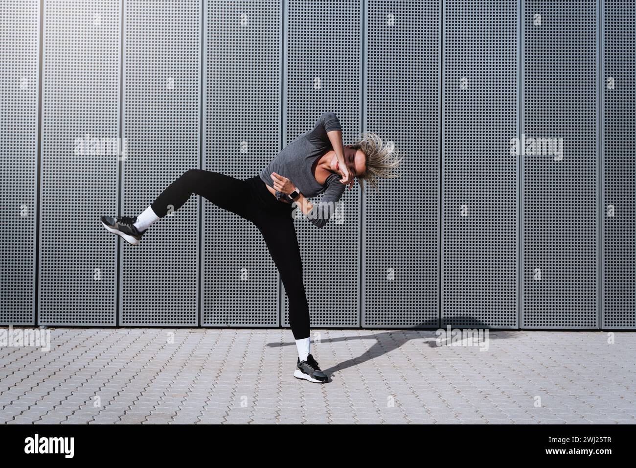 Expressive woman dancer performing against background with modern steel ...