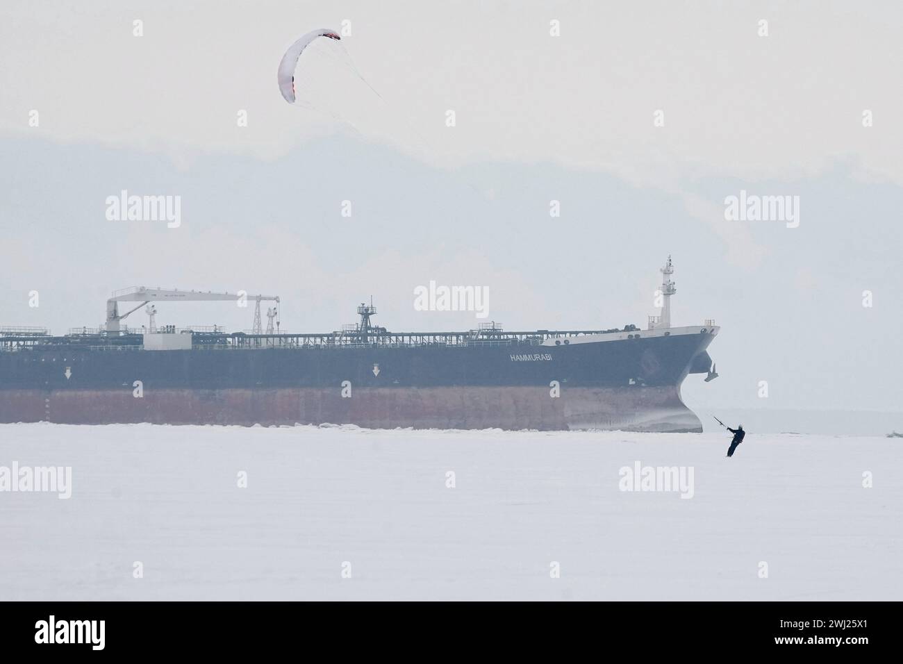 A man skis with a kite on the ice of the Gulf of Finland past Hammurabi ...