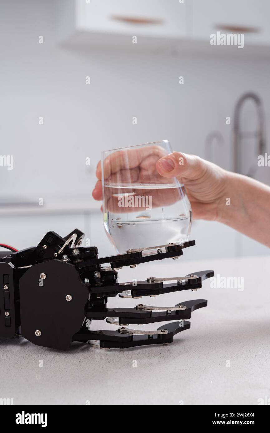 Robotic caregiver extending a hand with a glass of water to young woman ...