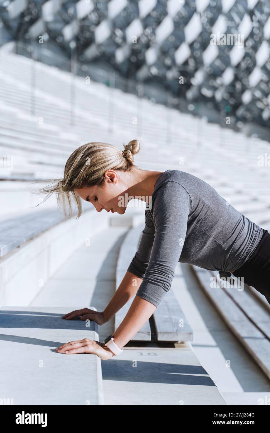 Woman athlete wearing female sportswear doing push-ups during ...