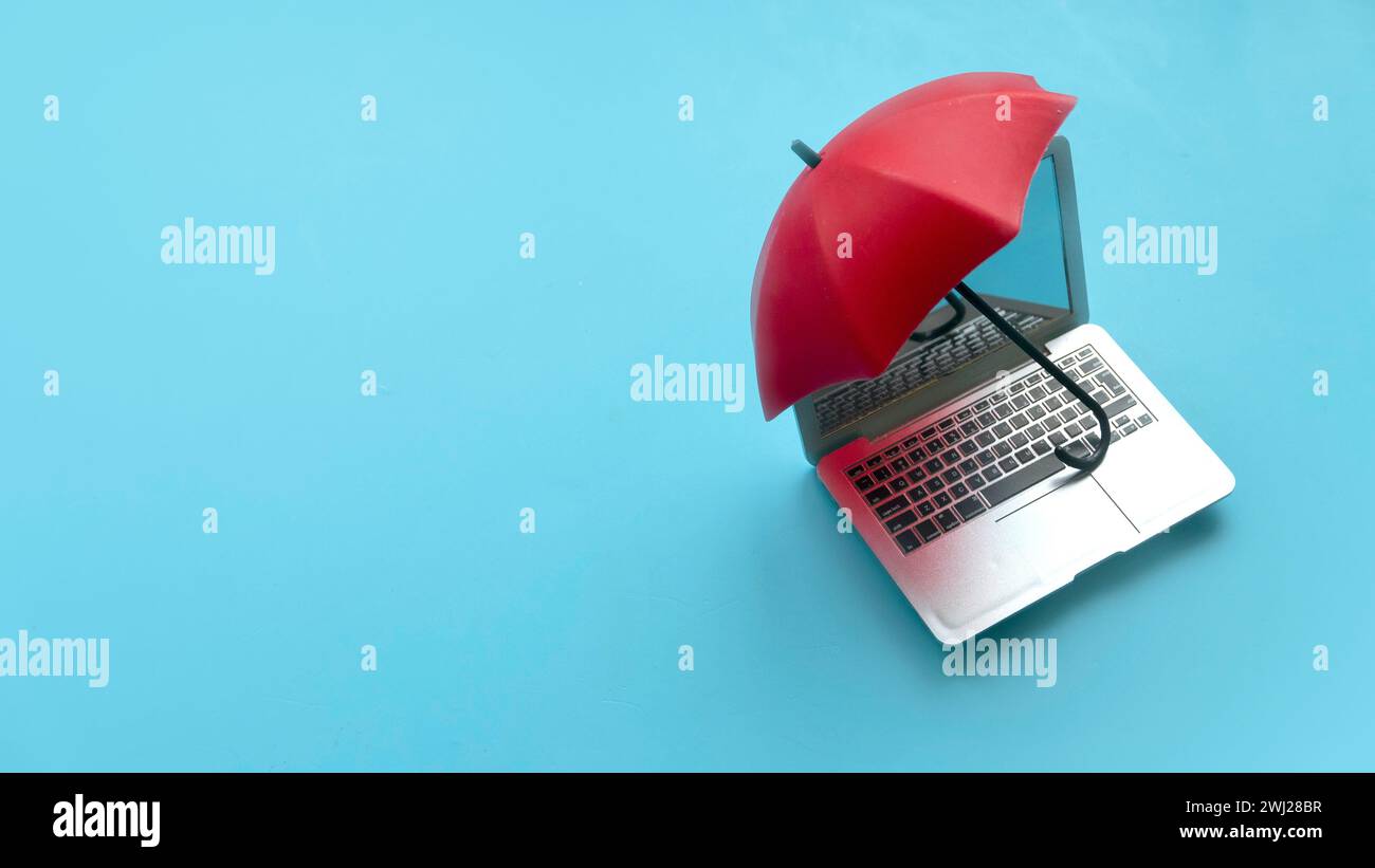 Computer and network security concept. Red umbrella cover the laptop ...
