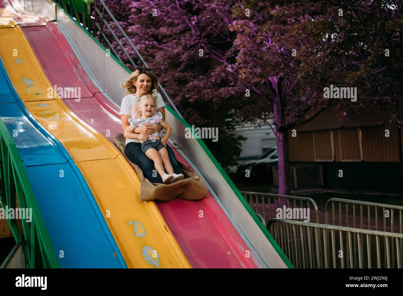 Mom and daughter sliding down fun slide at carnival Stock Photo - Alamy