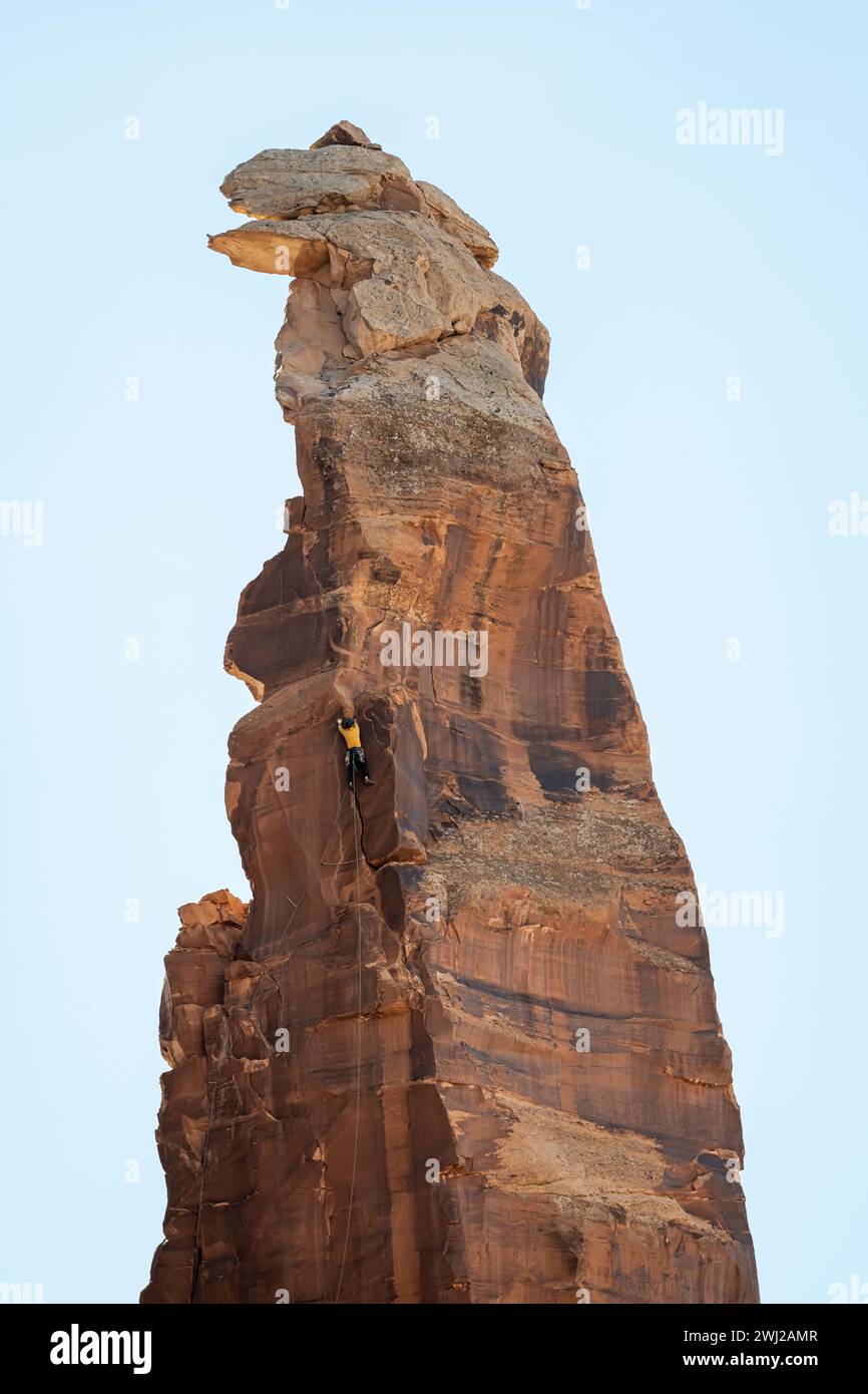 Low angle view of mountaineer reaching summit of tall rocky cliff Stock ...