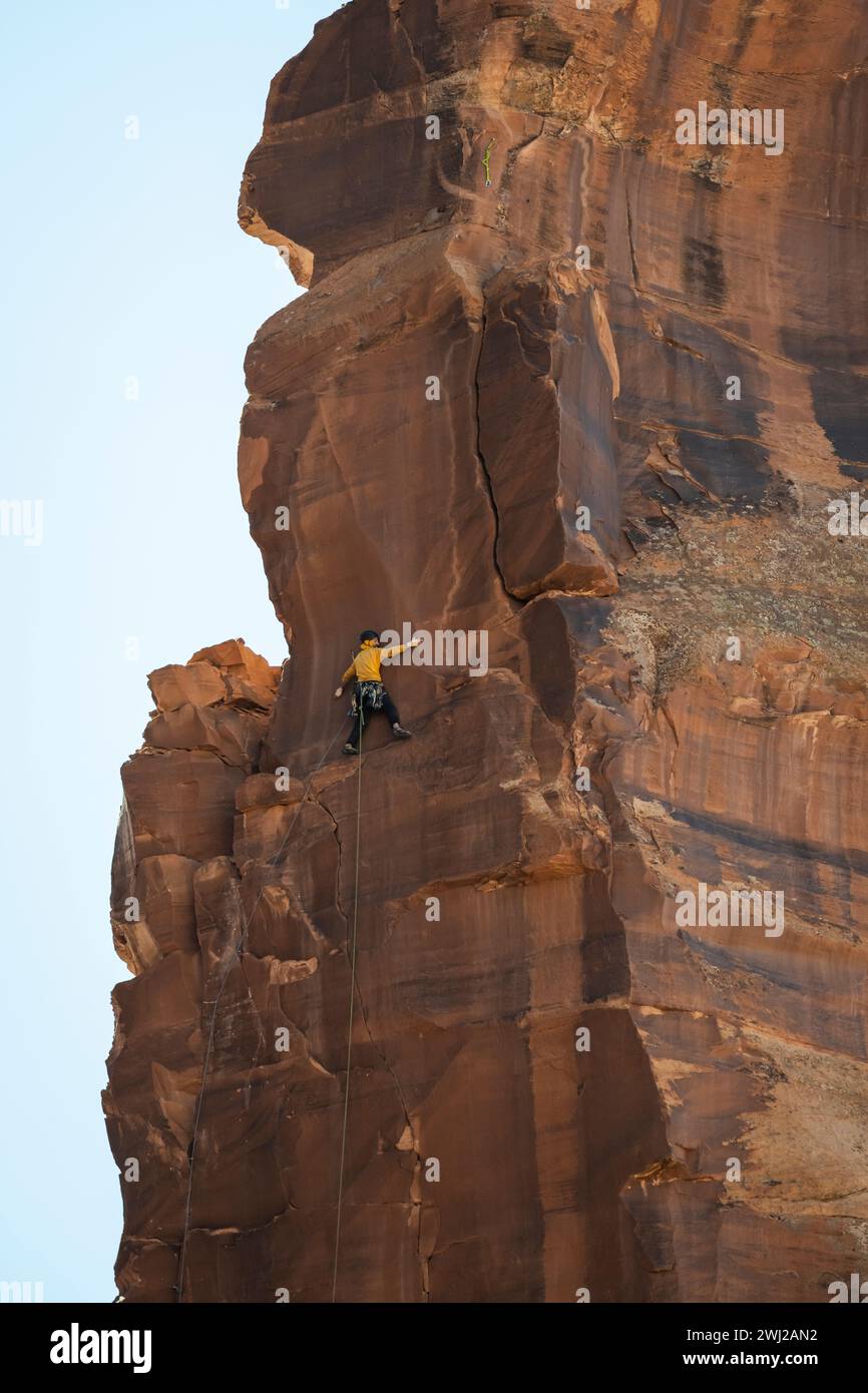 Low angle view of man rock climbing on cliff at desert Stock Photo - Alamy