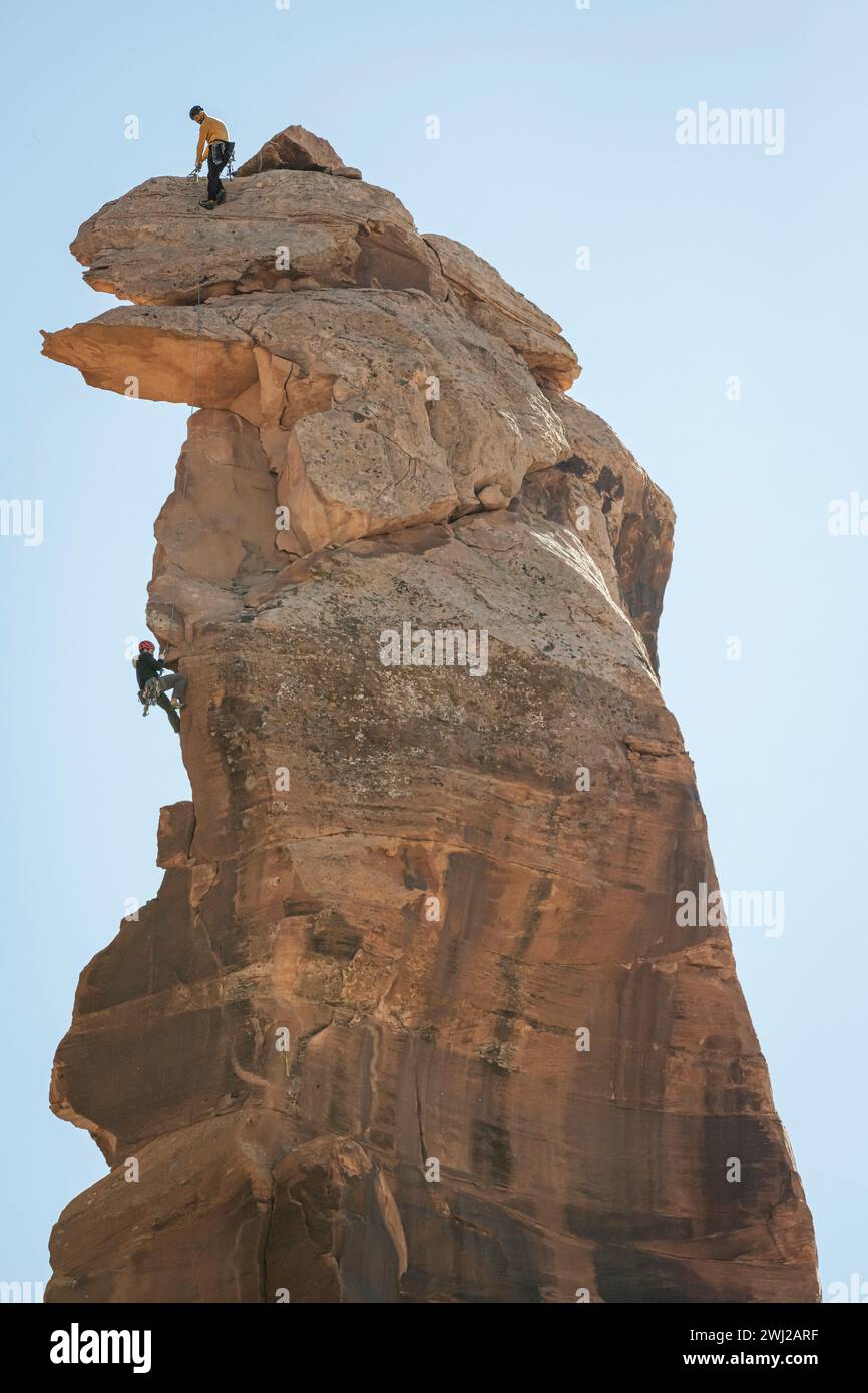 Rock climbers reaching summit of tall rocky cliff against sky Stock ...