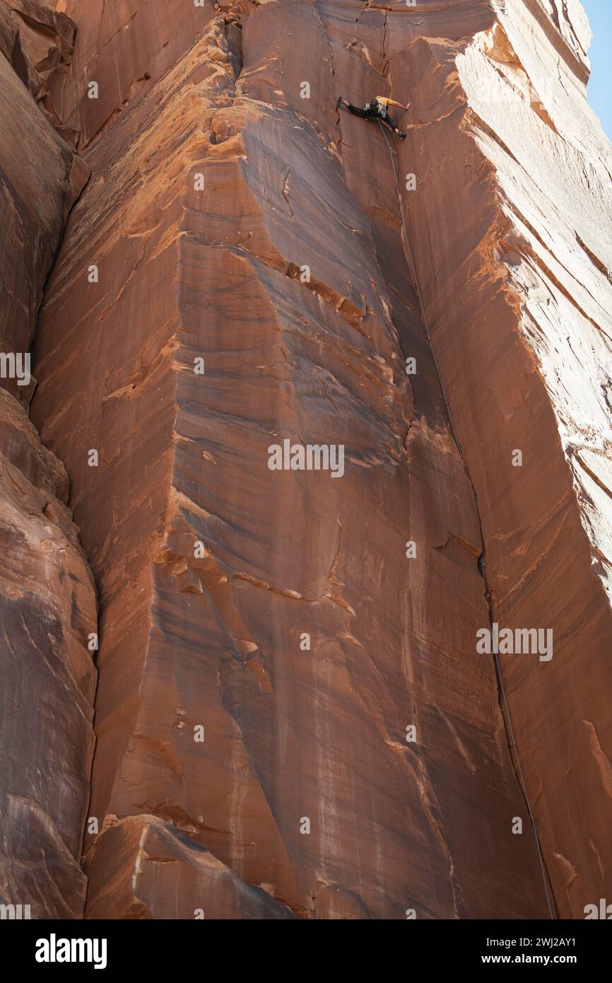 Low angle view of determined man climbing rocky cliff Stock Photo - Alamy
