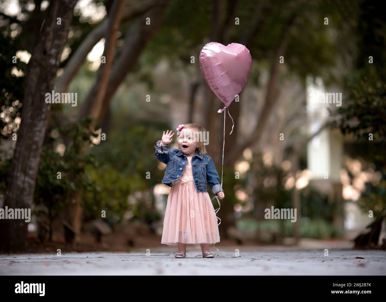 Little joyful girl waving holding a pink valentine's day balloon Stock ...