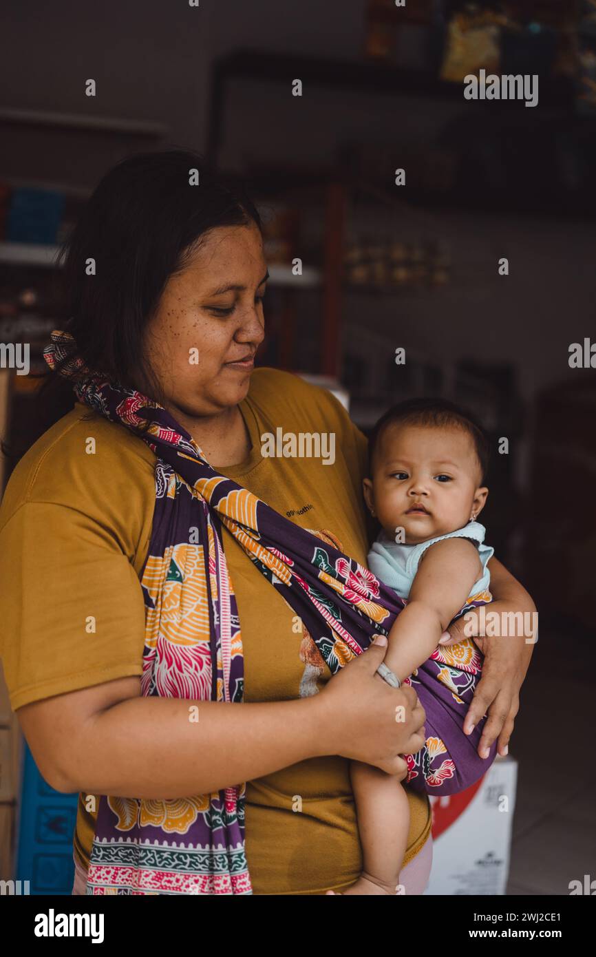 Balinese woman holding a small baby in her arms, motherhood portrait ...