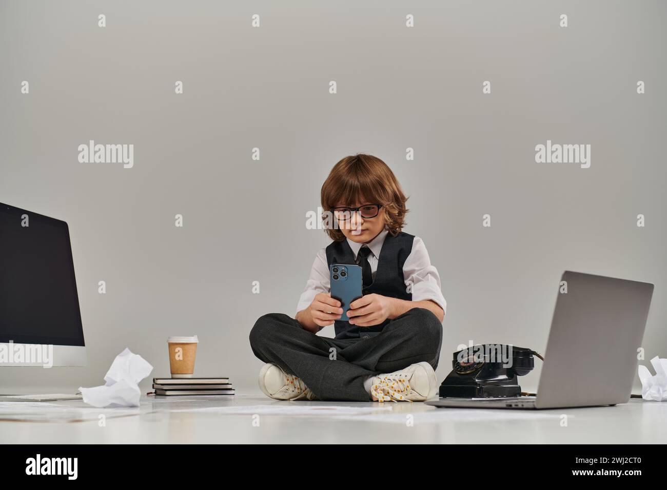 boy sitting on floor, engrossed in technology as he using both phone ...