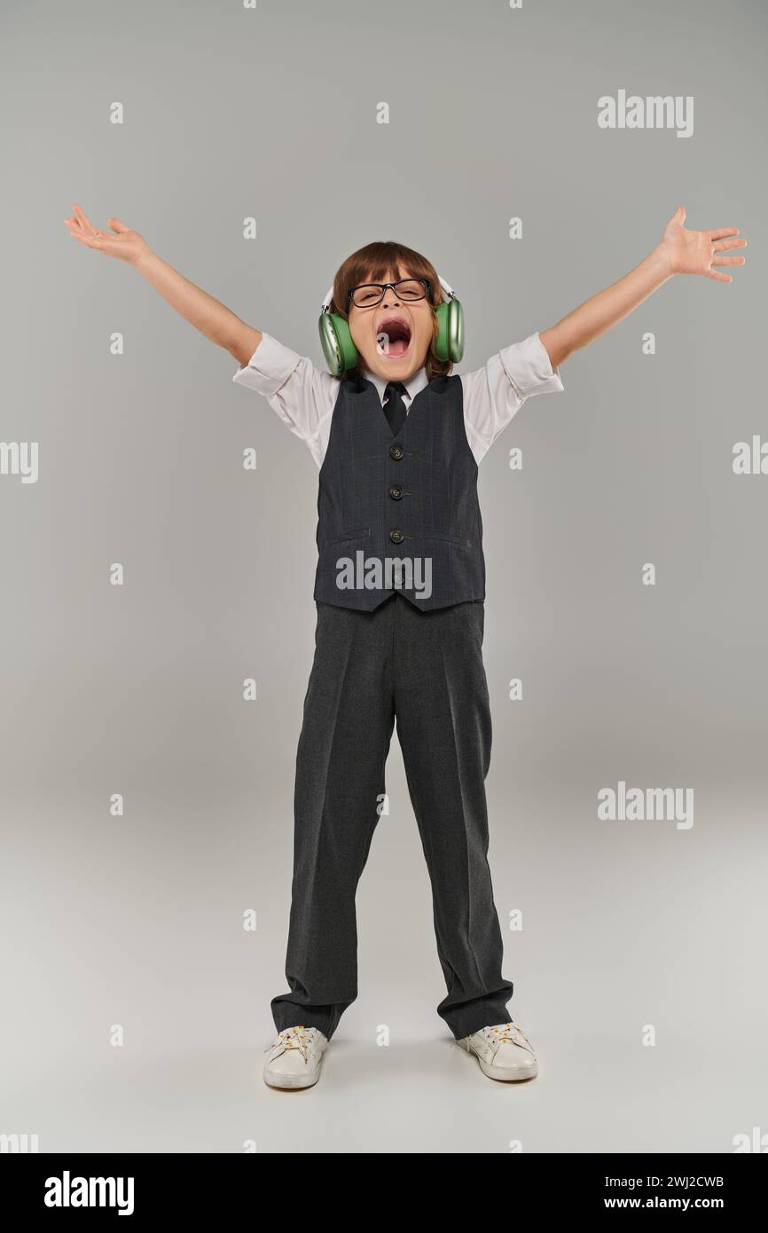 joyous boy singing as raising his arms in triumph while listening to ...