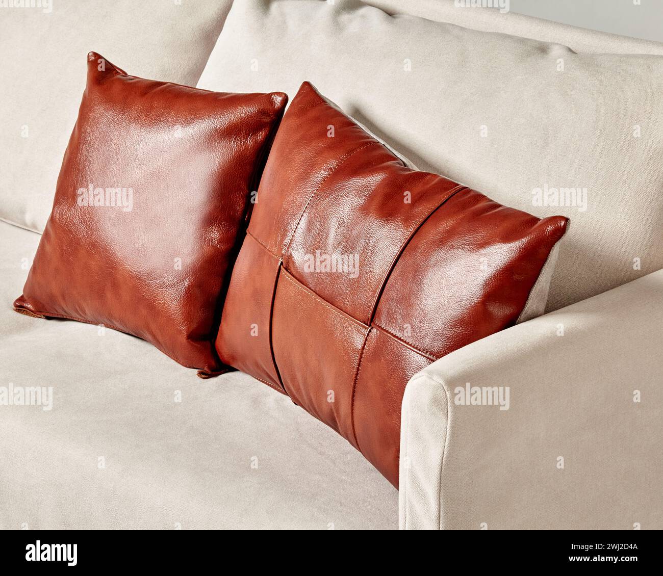 Brown leather pillows complementing modern light-grey sofa Stock Photo - Alamy