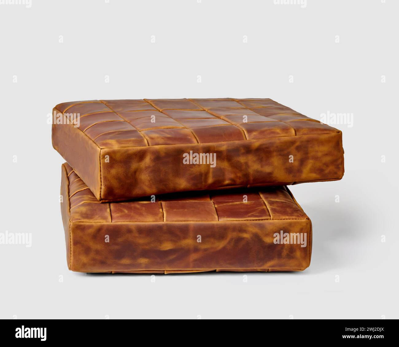 Two stacked functional brown leather square seat cushions on white ...