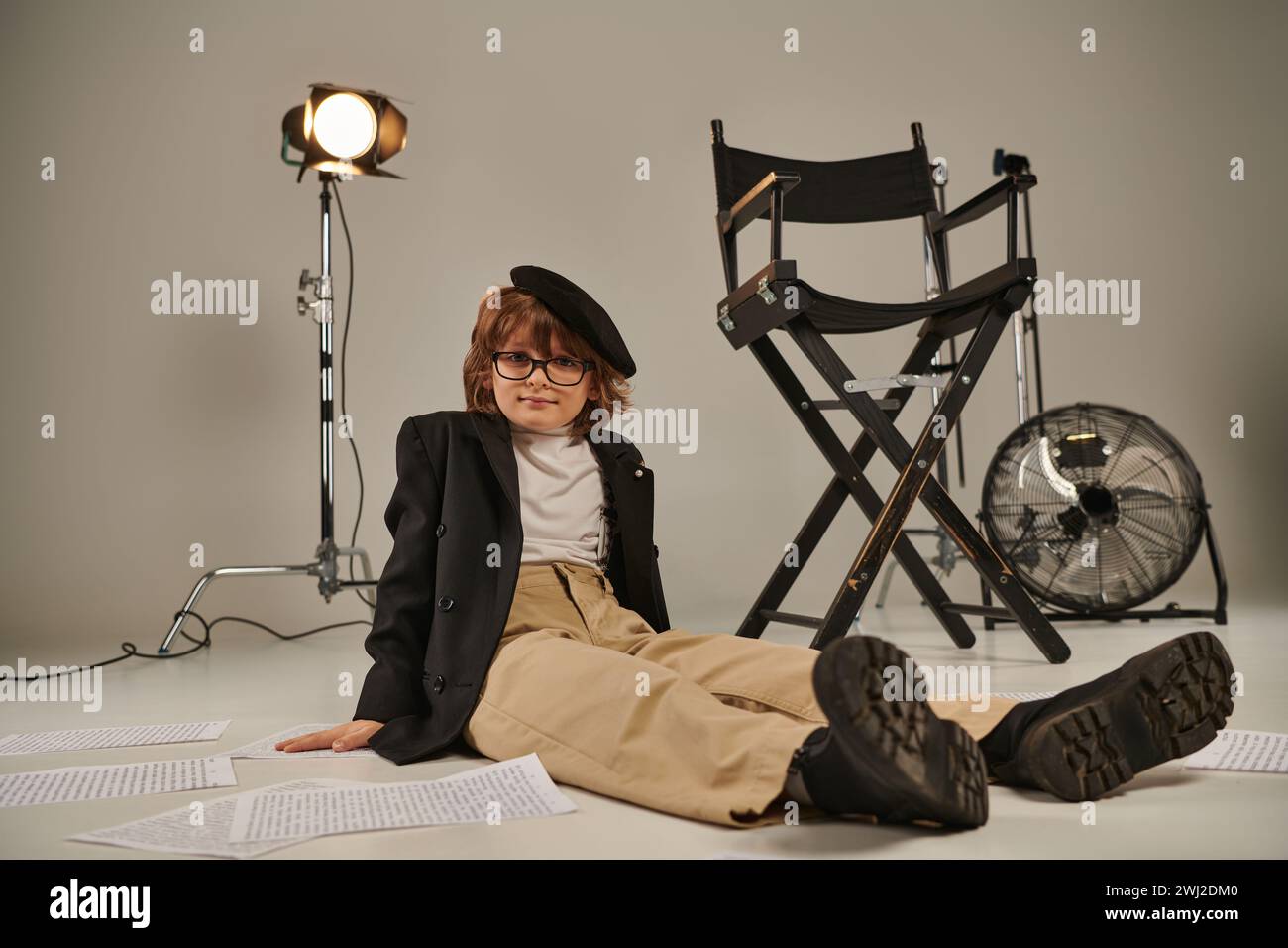 boy in glasses and beret sitting on floor surrounded by screenplay, boy ...