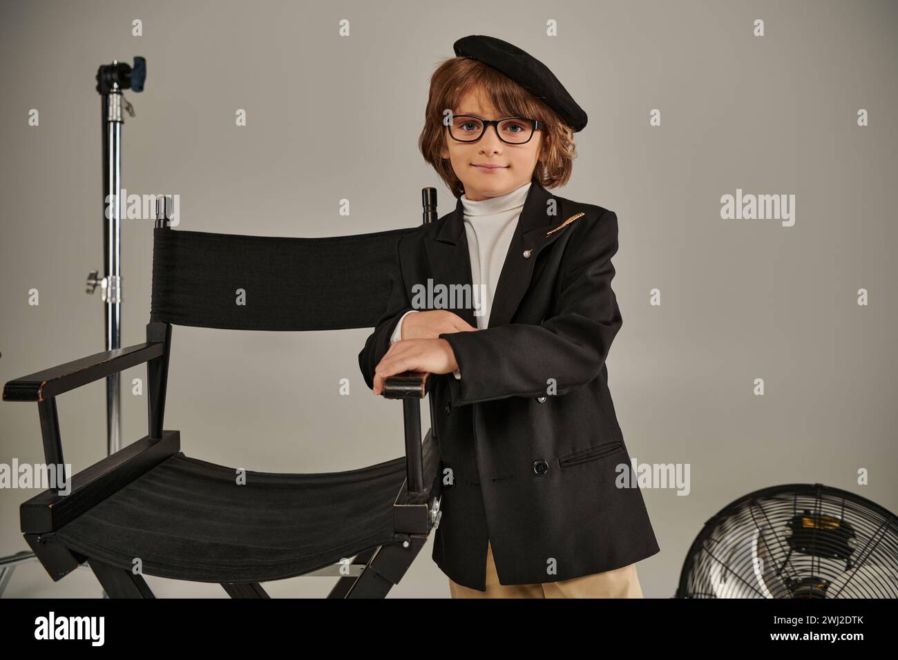cute boy in beret and stylish attire stands confidently near director ...