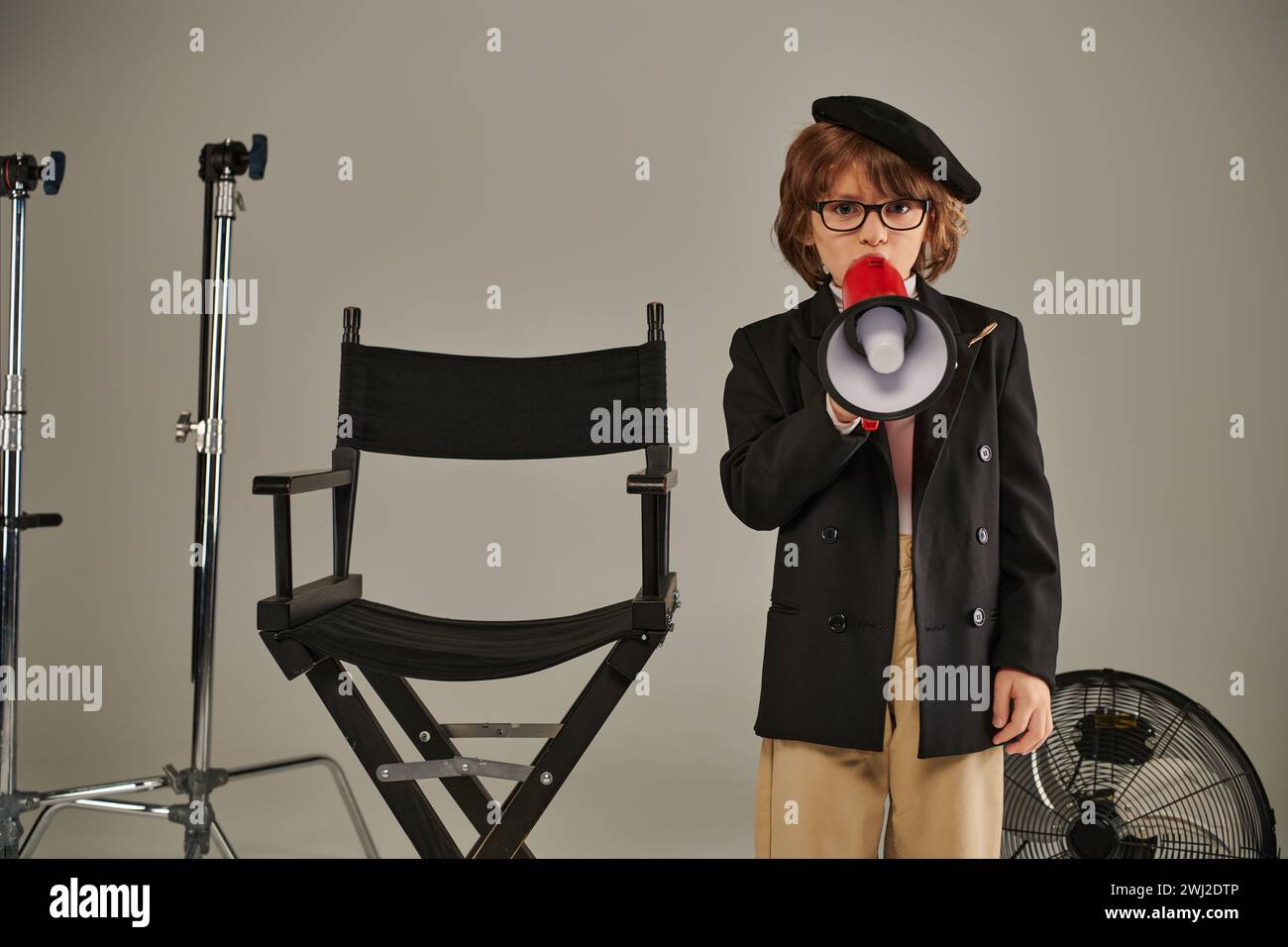 boy as filmmaker stands confidently near director chair and speaking in ...