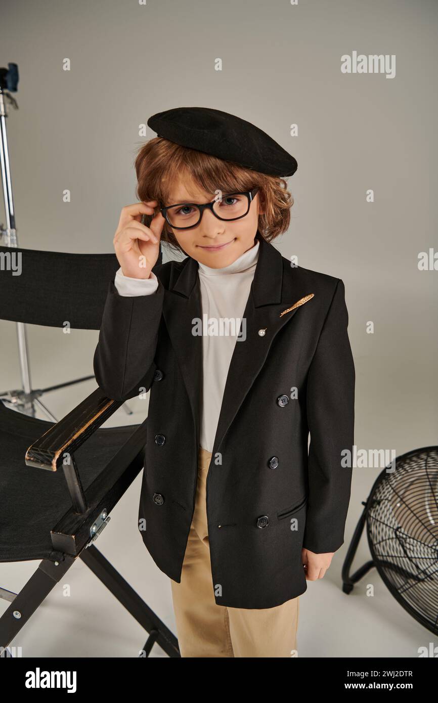 stylish boy wearing jacket and beret as he smiling on grey backdrop ...