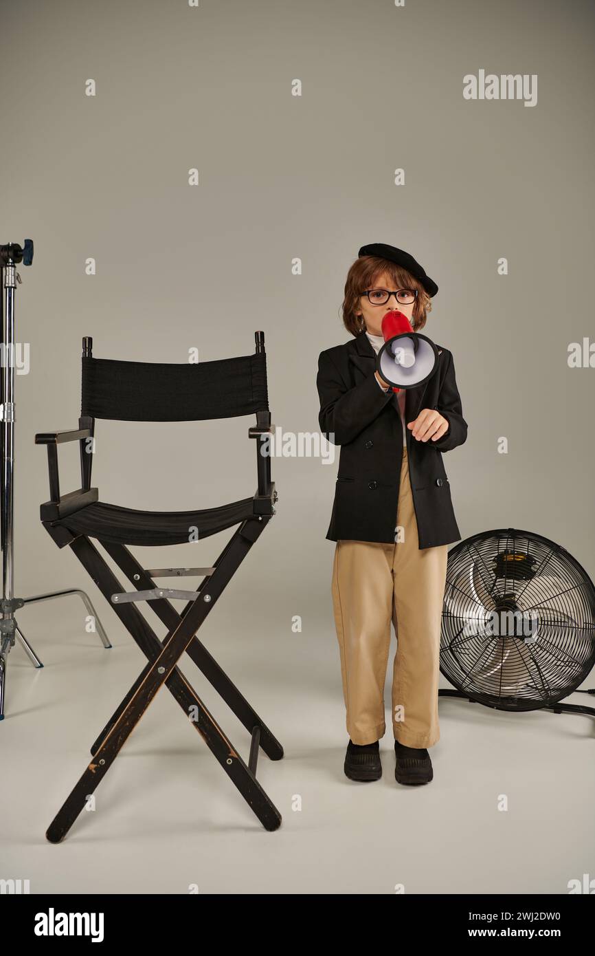 stylish child stands confidently near director chair and speaking in ...