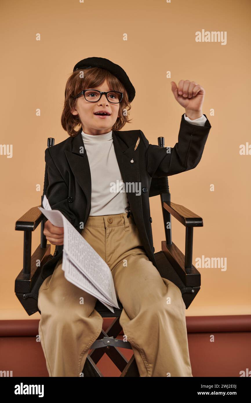 determined boy sits in director chair with papers in hands, ready to ...