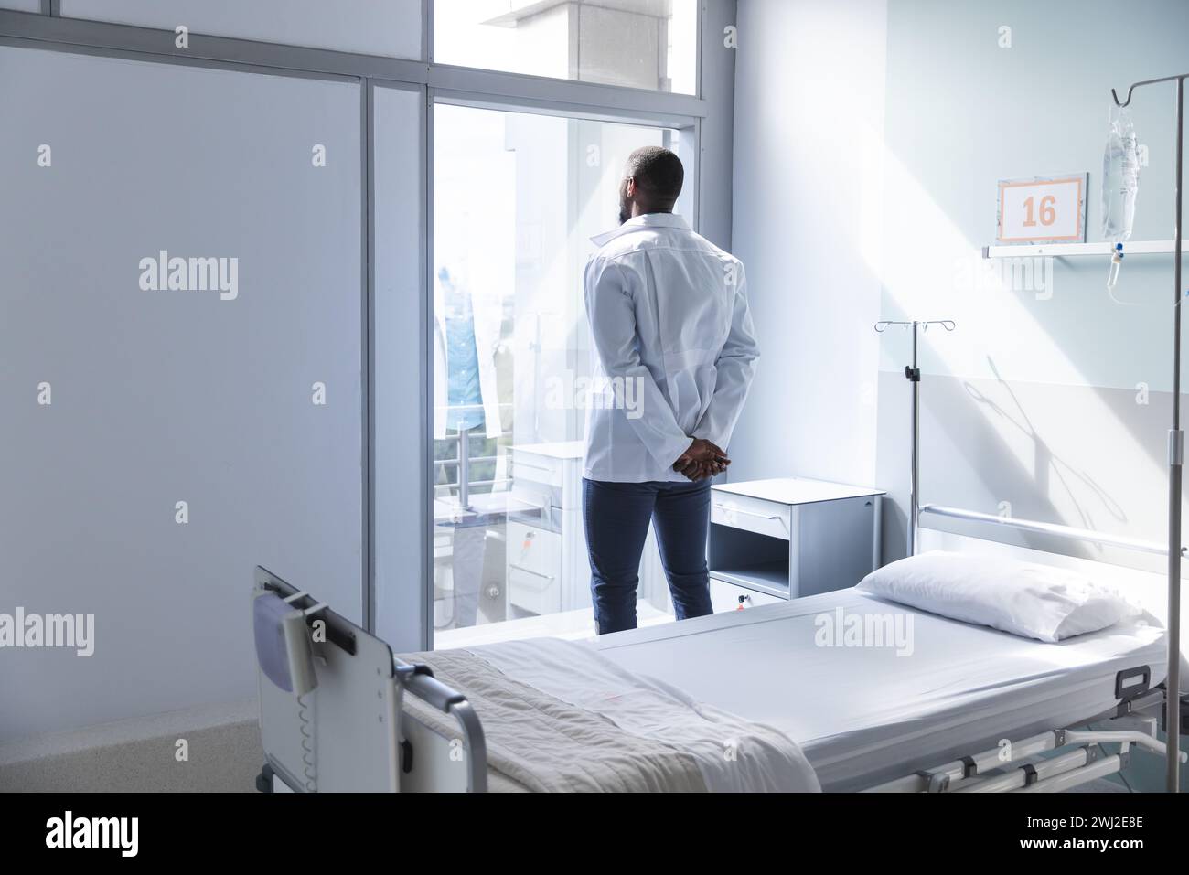 Thoughtful african american male doctor looking through window in ...