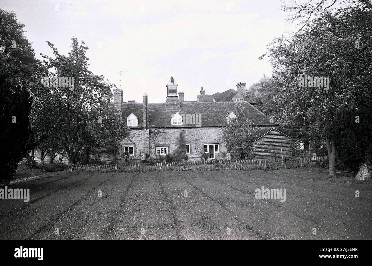 1960s, historical, exterior, rear view, over field, of an old three ...