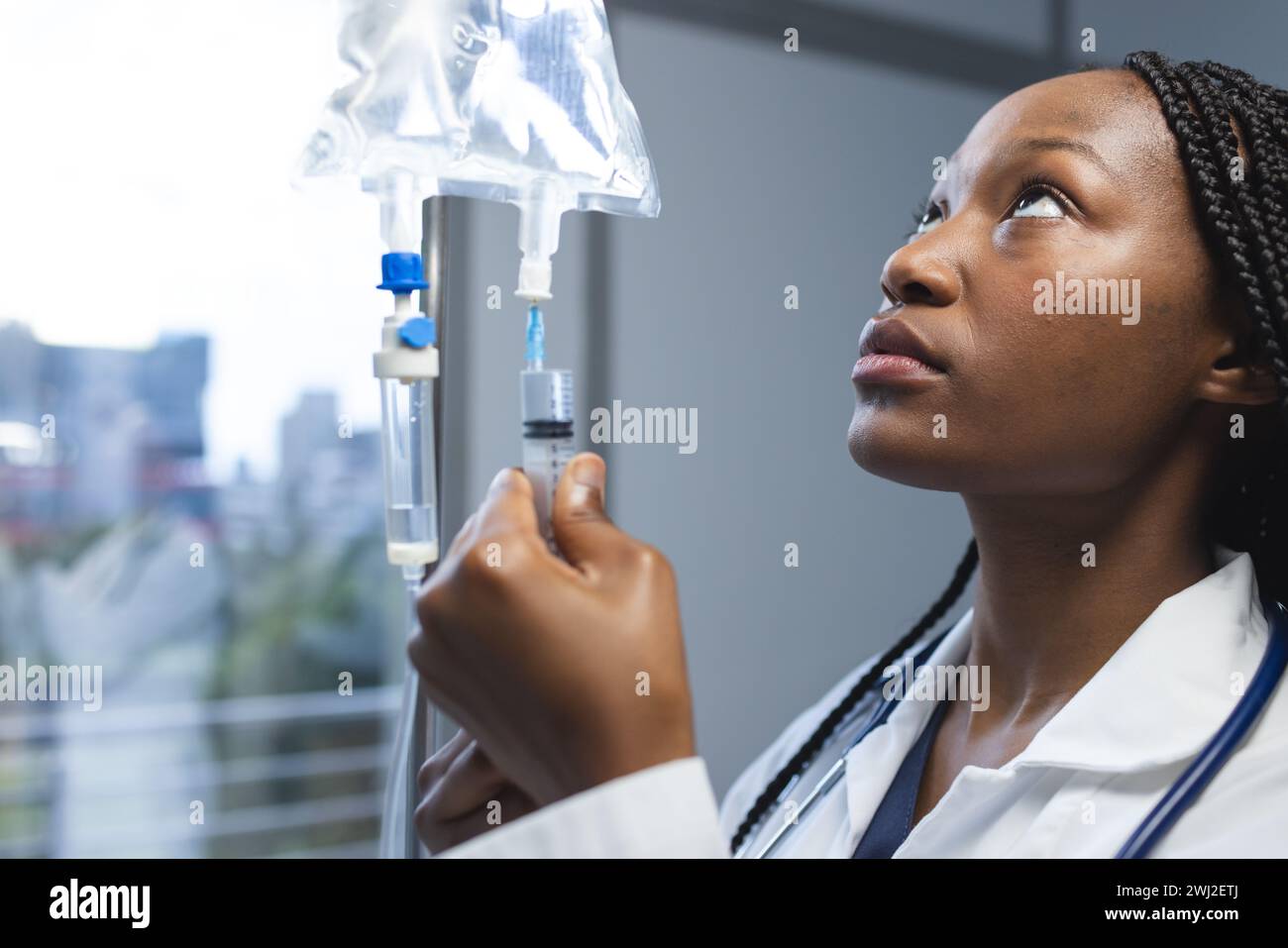 African american female doctor wearing lab coat applying drip in ...