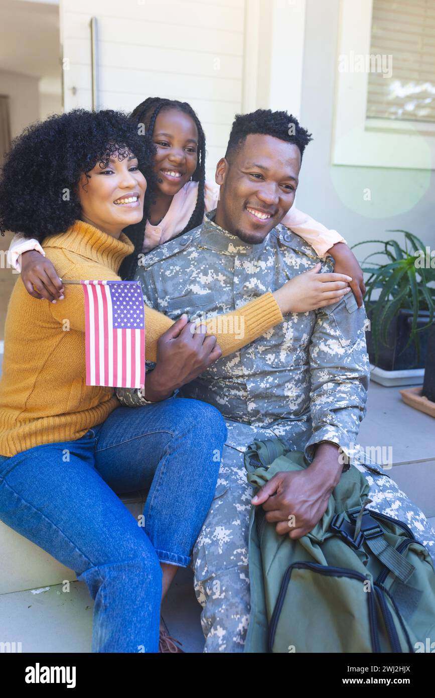 Happy african american male soldier embracing family outside home with ...